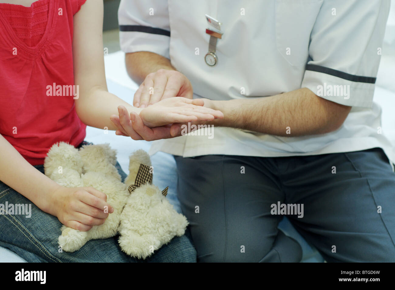 Young girl patient in hospital ward having her pulse checked by a nurse ...