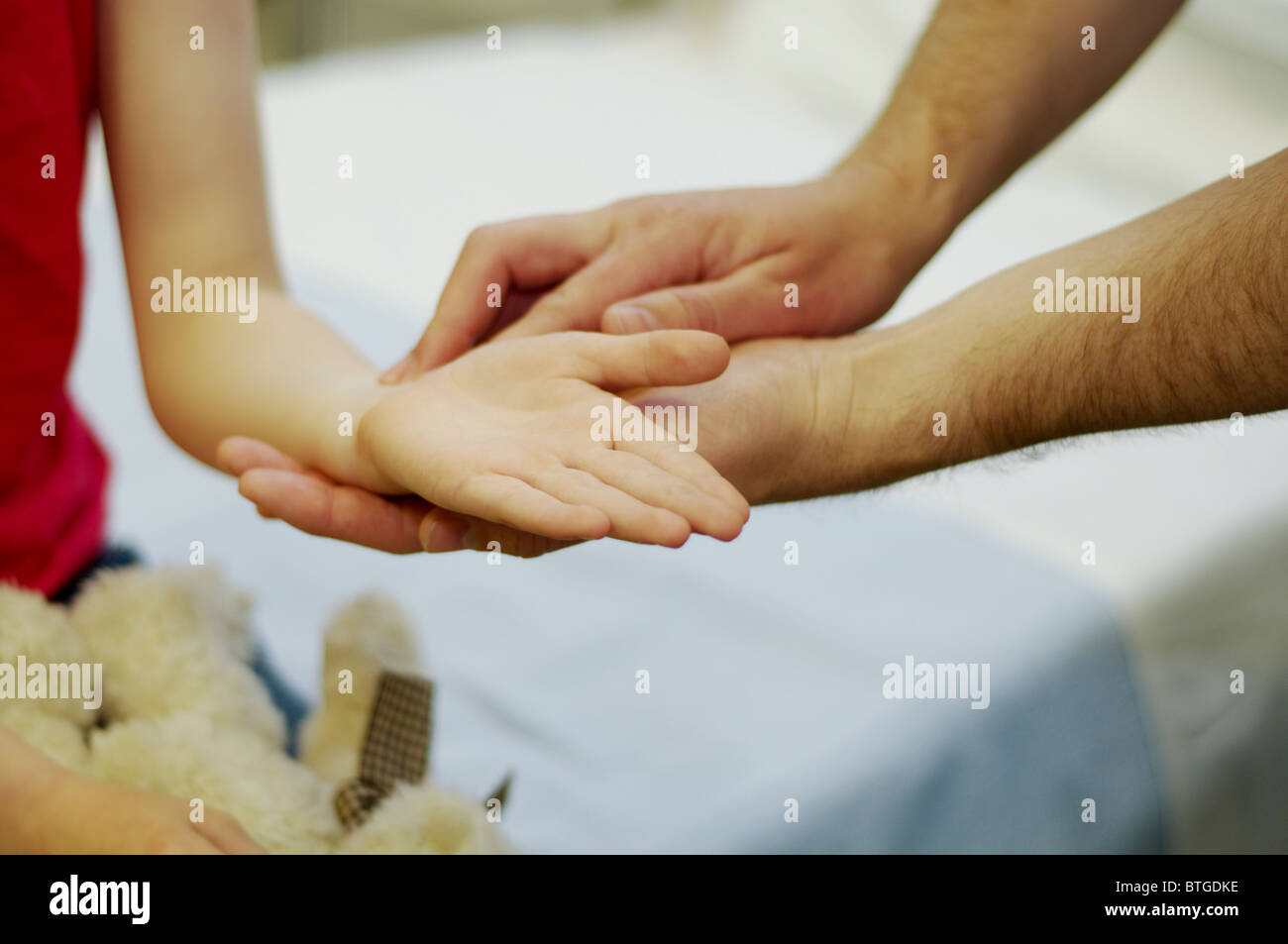 Young girl patient in hospital ward having her pulse checked by a nurse ...