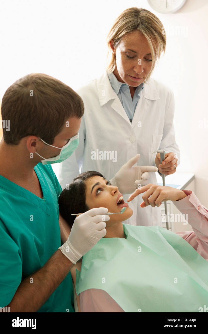 Dental professionals with patient pointing to mouth Stock Photo - Alamy