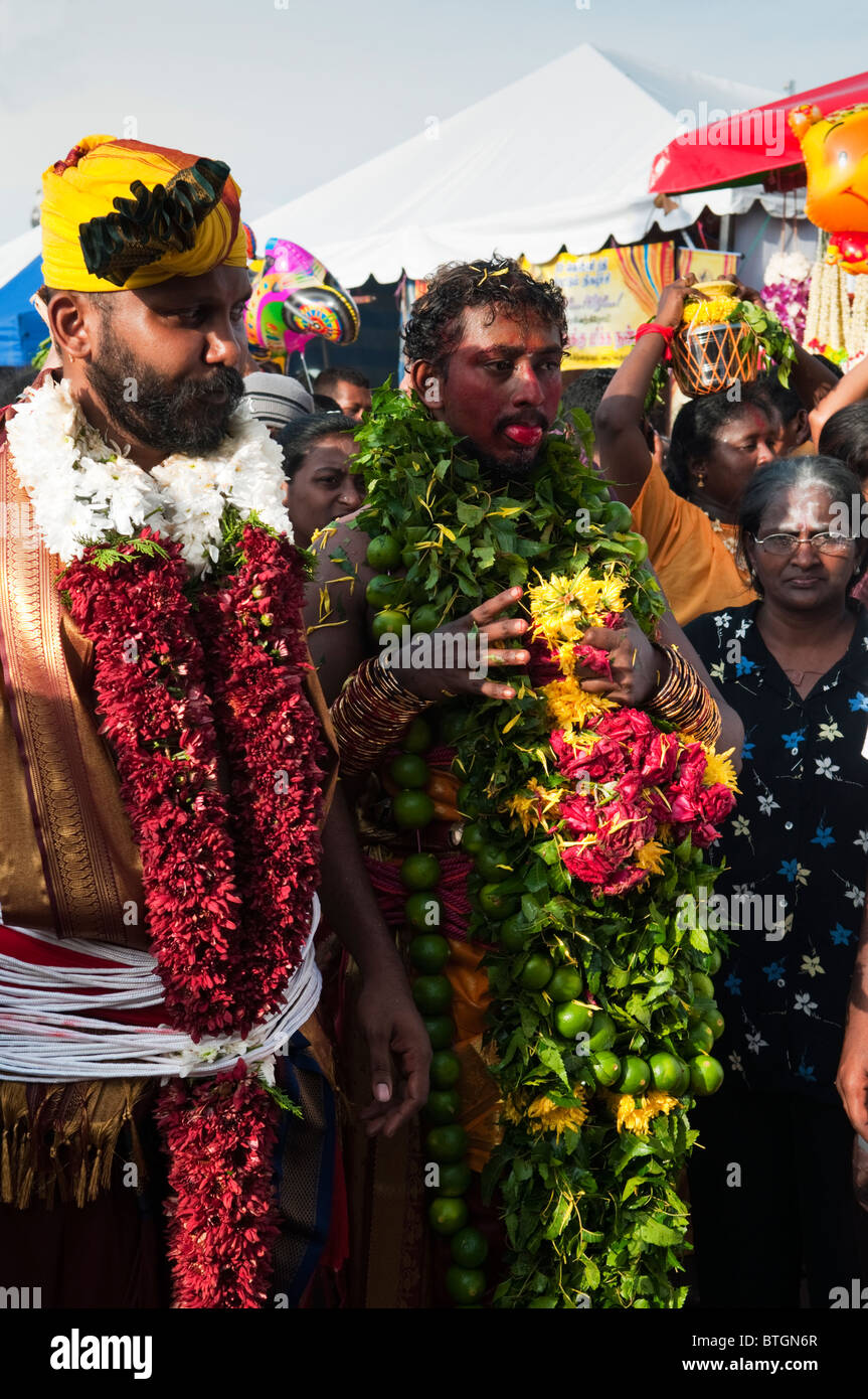 Hindu devotees carrying wearing garlands of fruits and flowers during ...