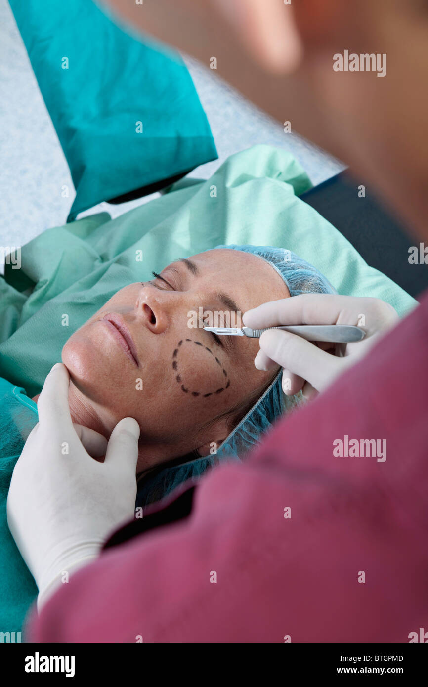 Surgeon holding scalpel to patient's face Stock Photo - Alamy