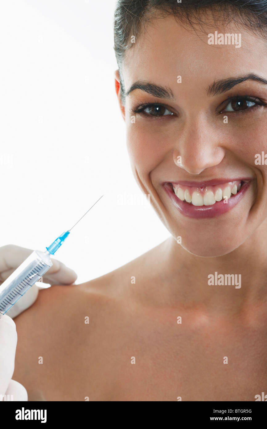 Hand holding botox syringe to young woman's face Stock Photo - Alamy