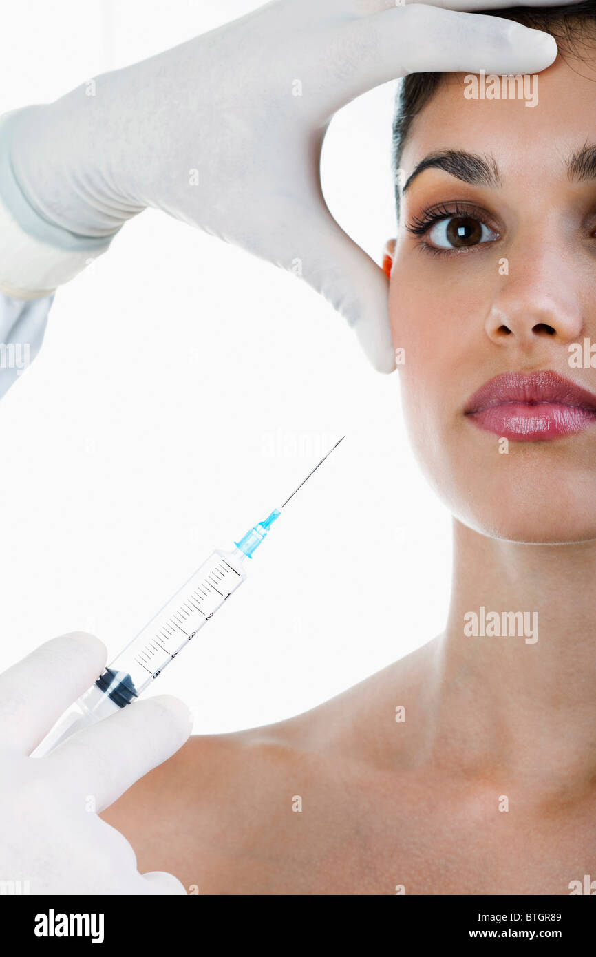 Hand holding botox syringe to young woman's face Stock Photo - Alamy