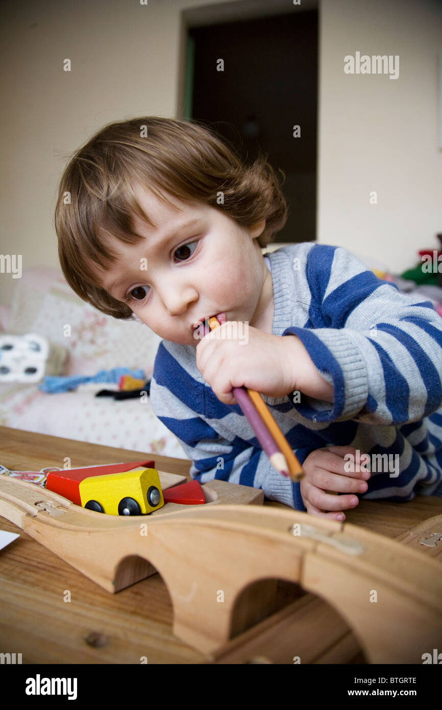 22 month baby boy putting color pencils in his mouth Stock Photo - Alamy
