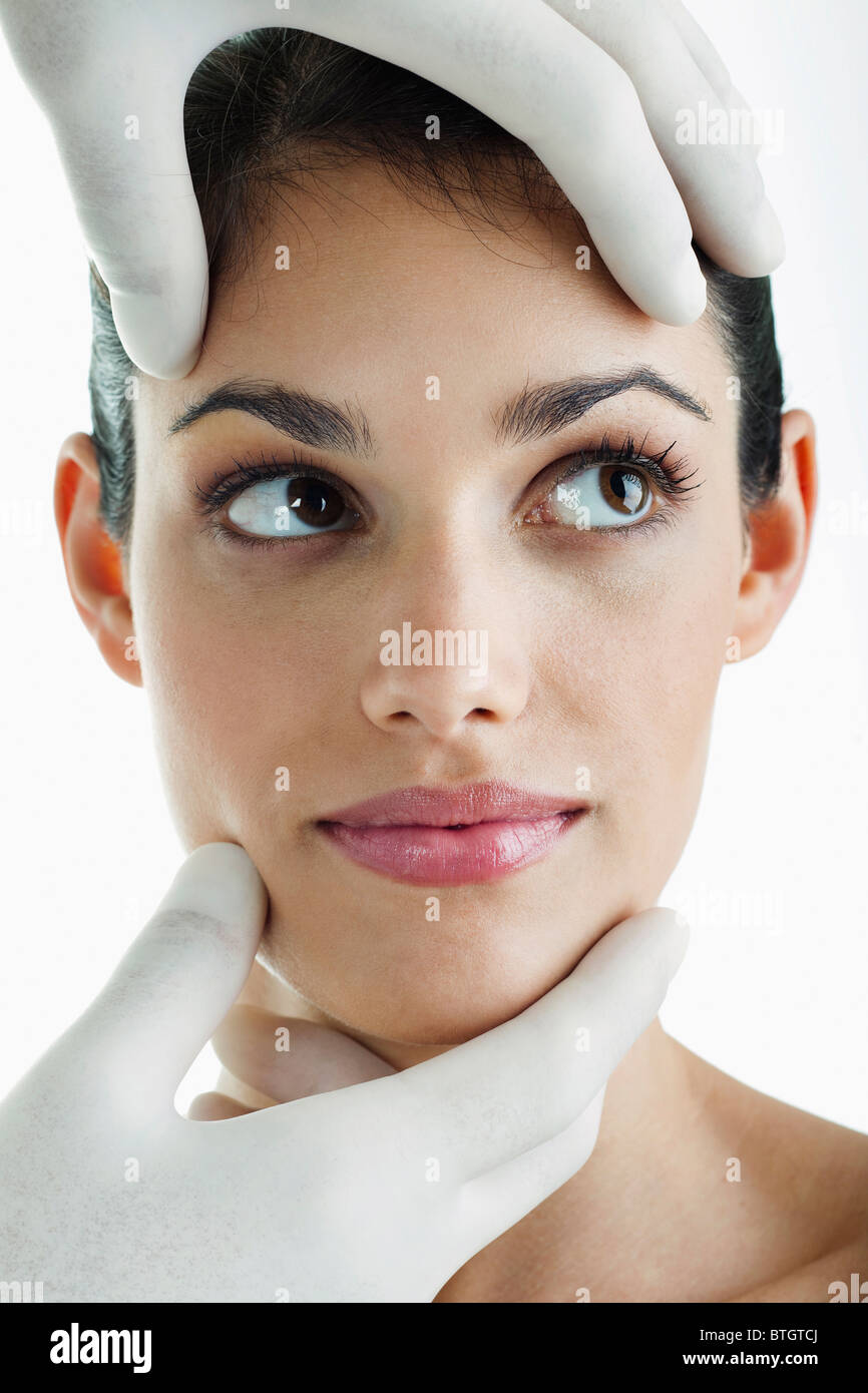 Hands wearing surgical gloves holding young woman's face Stock Photo ...