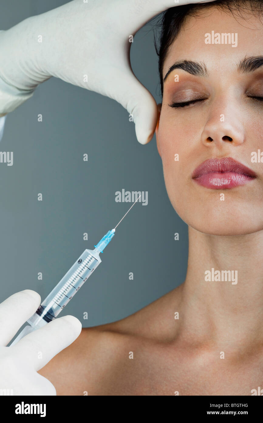 Hand holding botox syringe to young woman's face Stock Photo - Alamy