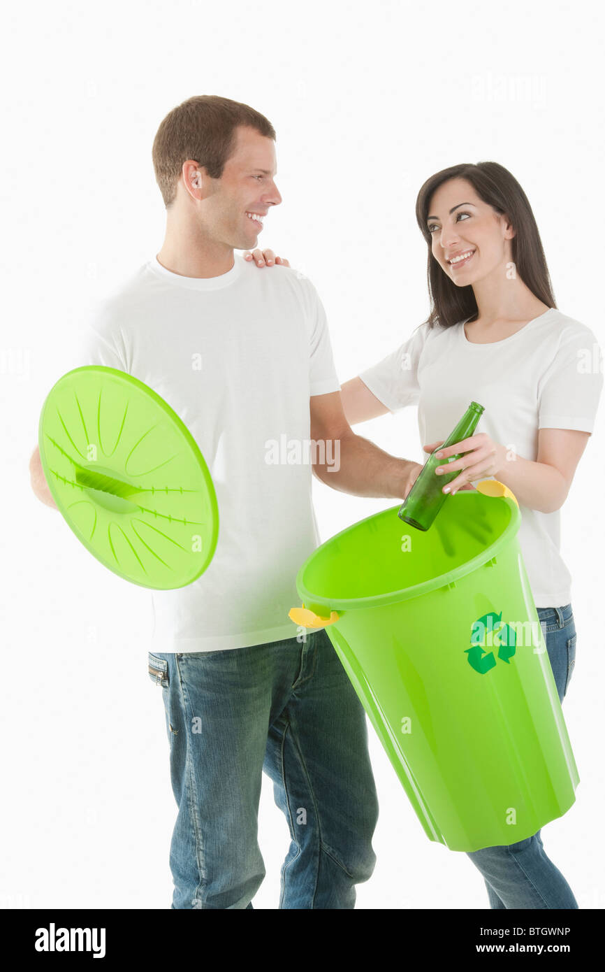 Couple throwing glass bottle in the recycling bin Stock Photo - Alamy