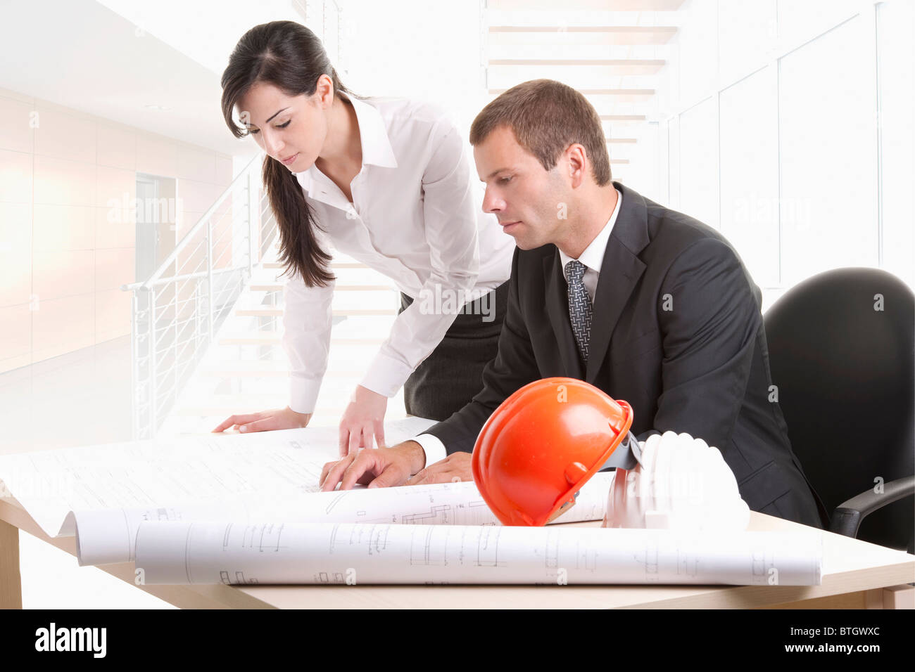 Man and woman looking over plans at desk Stock Photo - Alamy