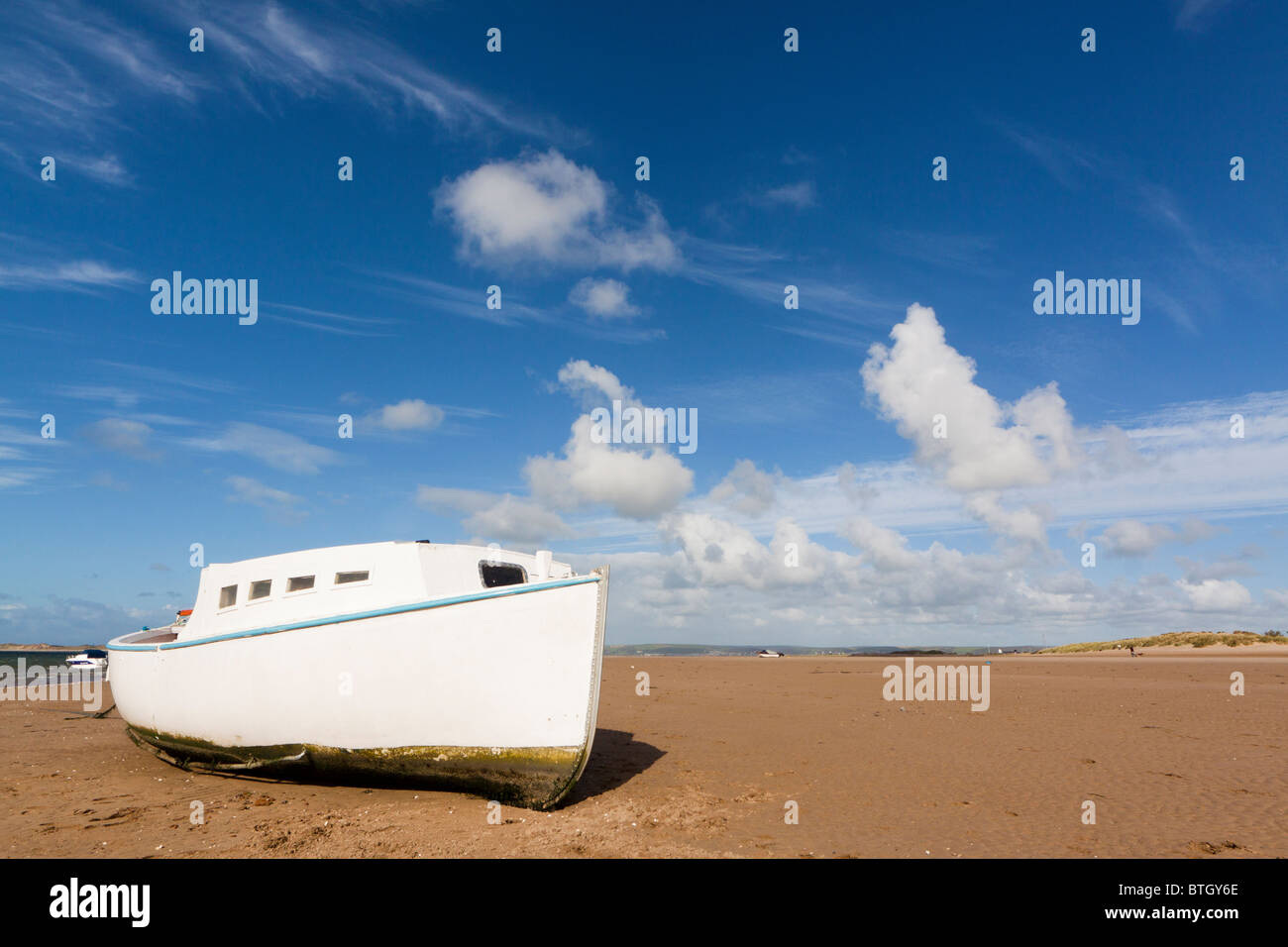 A small white boat lies on the golden sands of Instow beach in north ...