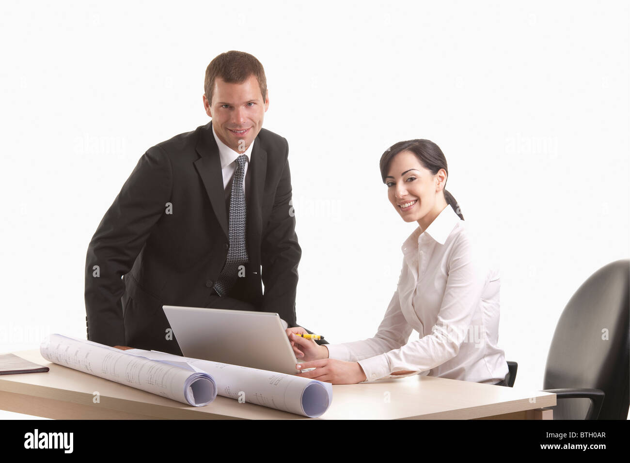 Man and woman with plans and laptop at desk Stock Photo - Alamy