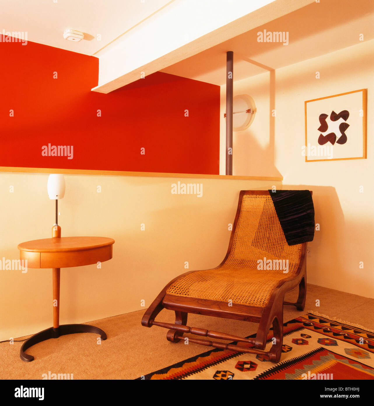 Small wood table and chaise-longue in modern living room with red wall ...