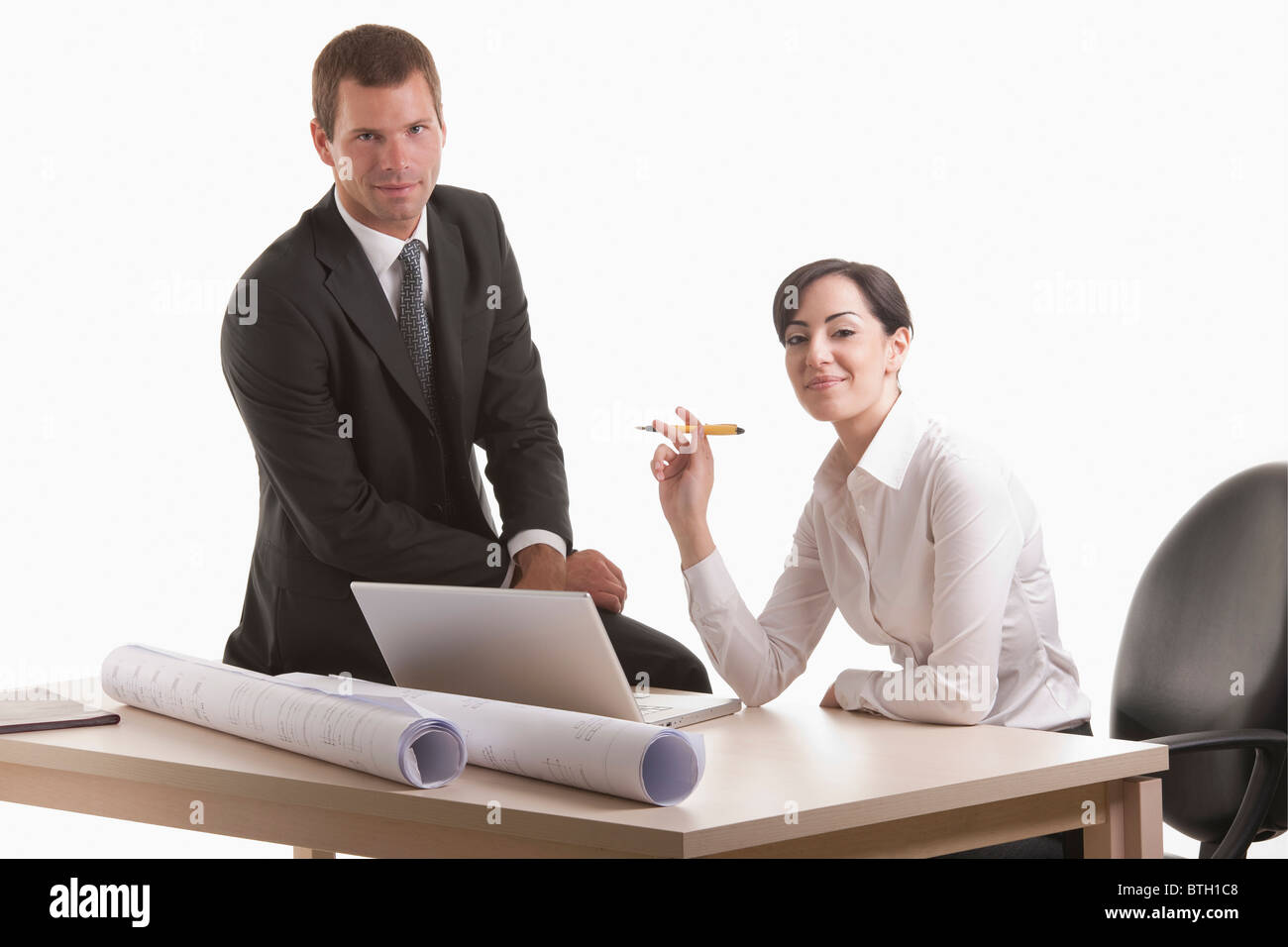 Man and woman with plans and laptop at desk Stock Photo - Alamy