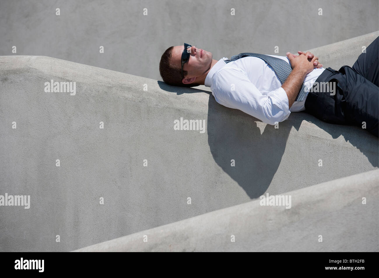 Man with tie and sunglasses lying down on wall Stock Photo - Alamy