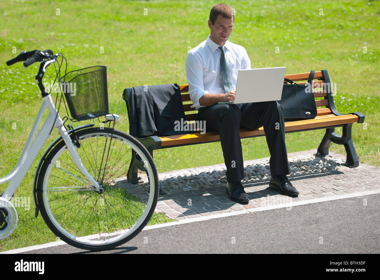 Businessman sitting on bench with laptop and bicycle Stock Photo - Alamy