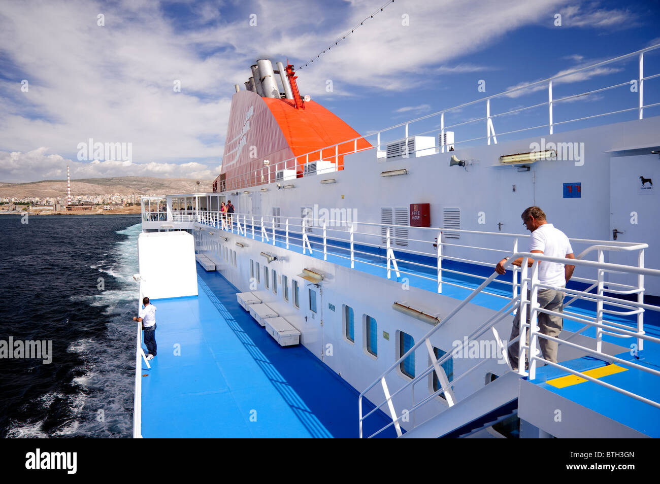 People on the deck of a ferry leaving Piraeus harbor for the Greek ...