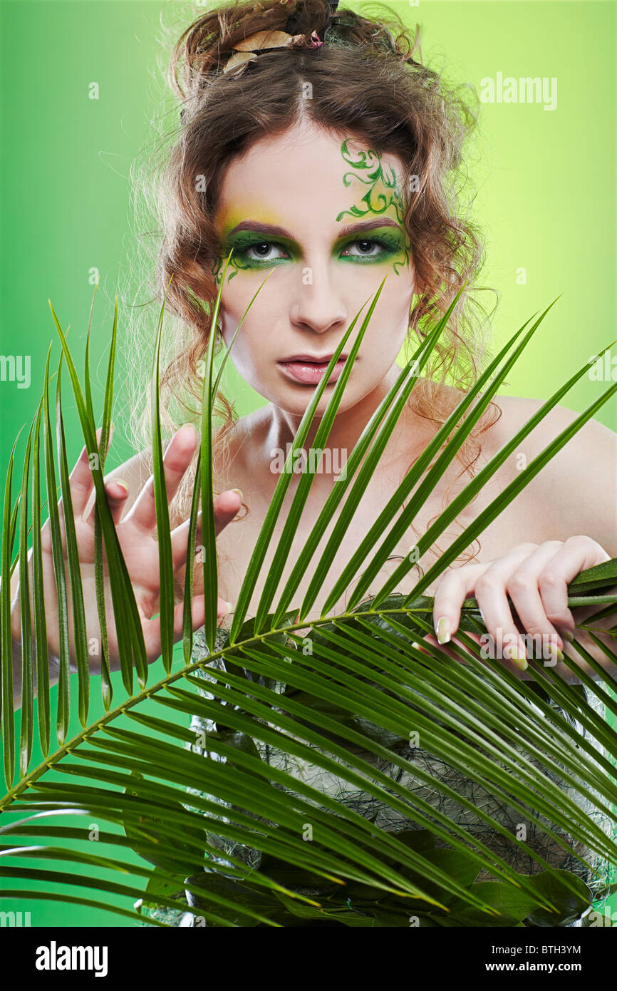 portrait of beautiful girl with fairy theme bodyart posing with fern ...