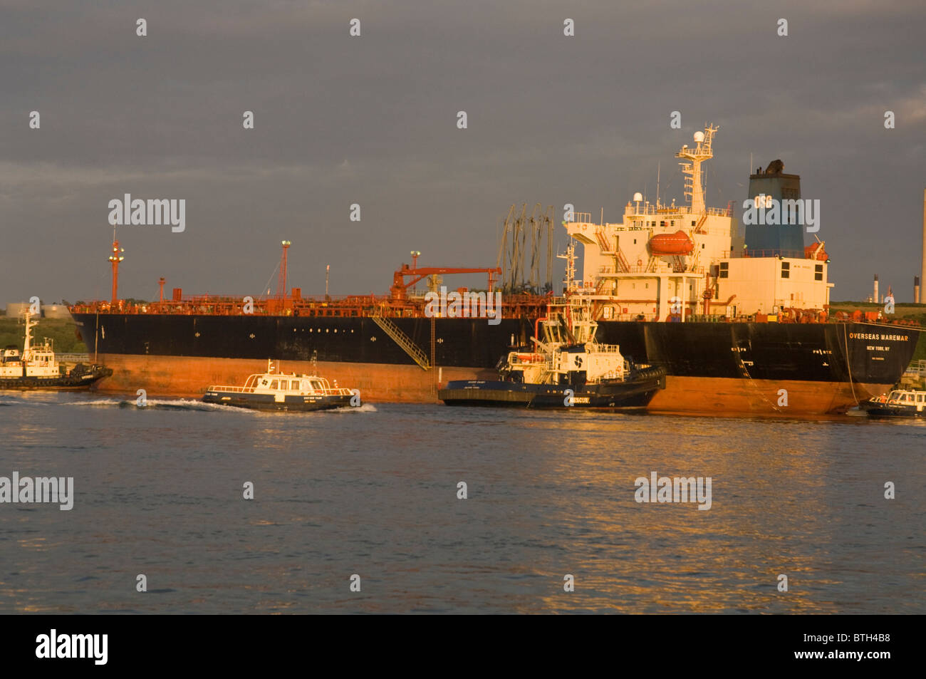 Tugs pushing oil tanker onto jetty, Texaco oil refinery, Milford Haven ...