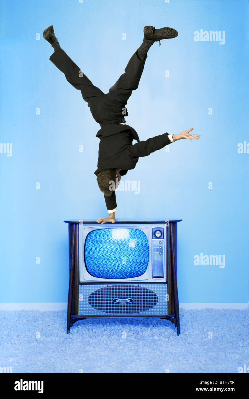 man doing a one handed hand stand on an old fashioned TV with static ...