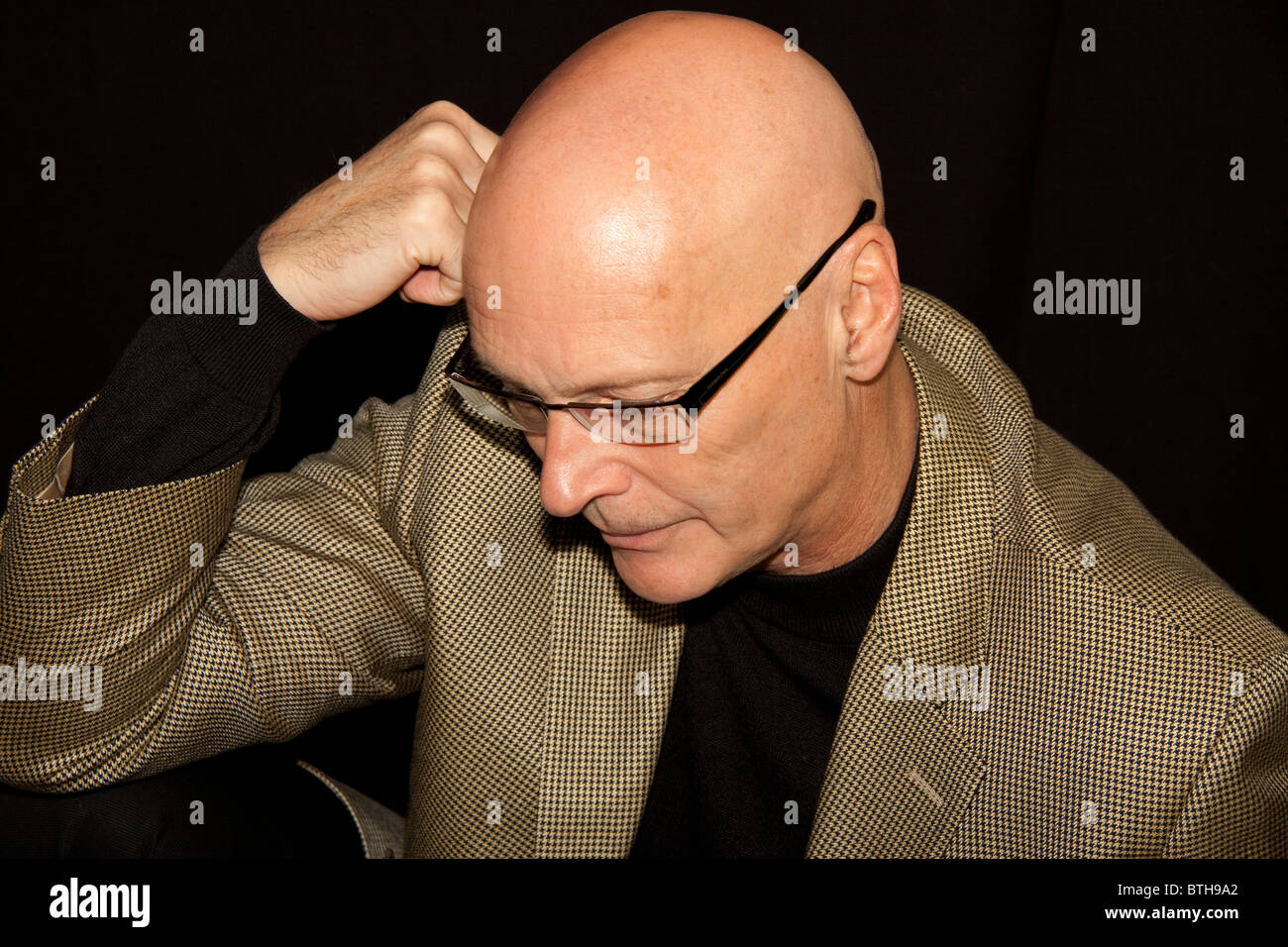 Serious, bald man with head in hands wearing eyeglasses Stock Photo - Alamy