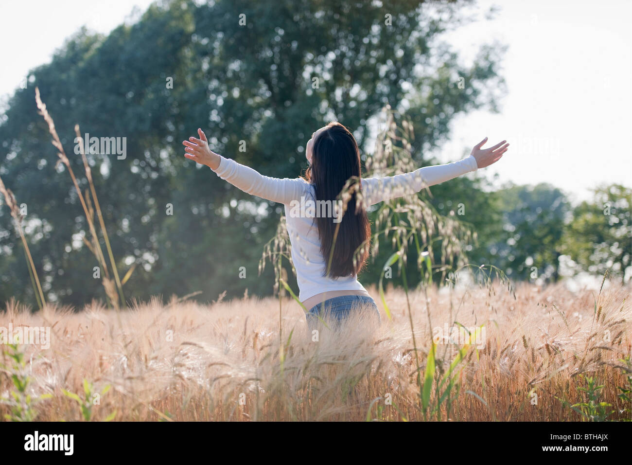 Woman with arms stretched out in wheat field Stock Photo - Alamy