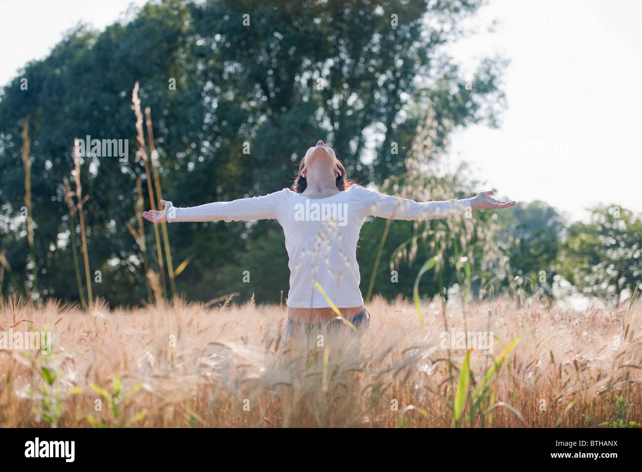 Woman with arms stretched out in wheat field Stock Photo - Alamy