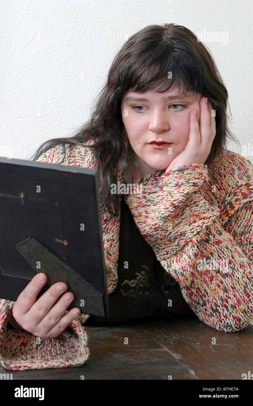 Teenager girl looking sadly at photo frame at home Stock Photo - Alamy