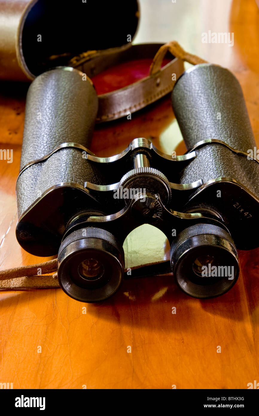Pair of binoculars and leather case on a wooden table Stock Photo - Alamy