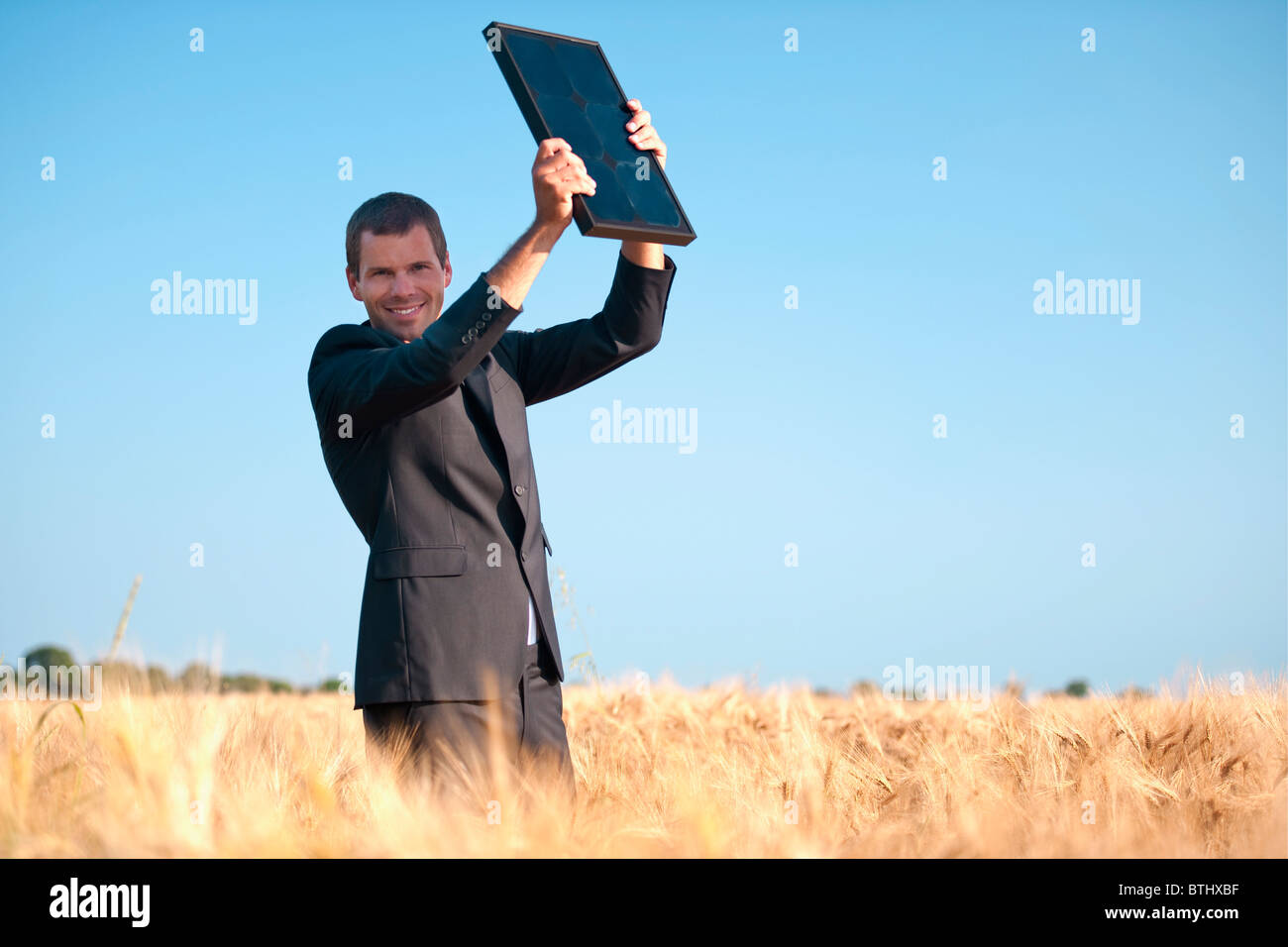 Man in suit holding up solar panel in wheat field Stock Photo - Alamy