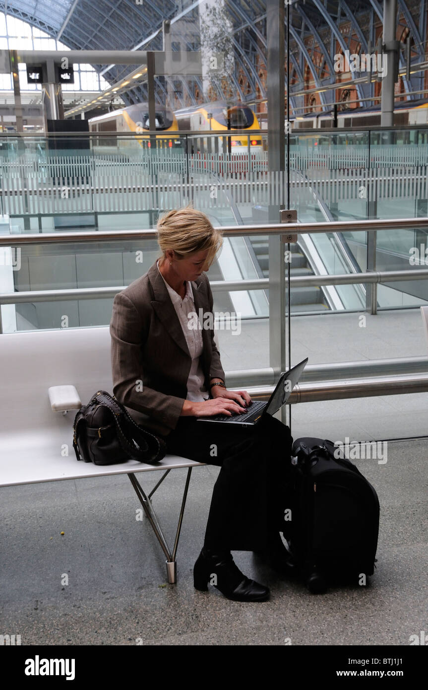 Portrait of a business woman sitting on a seat using a laptop computer ...