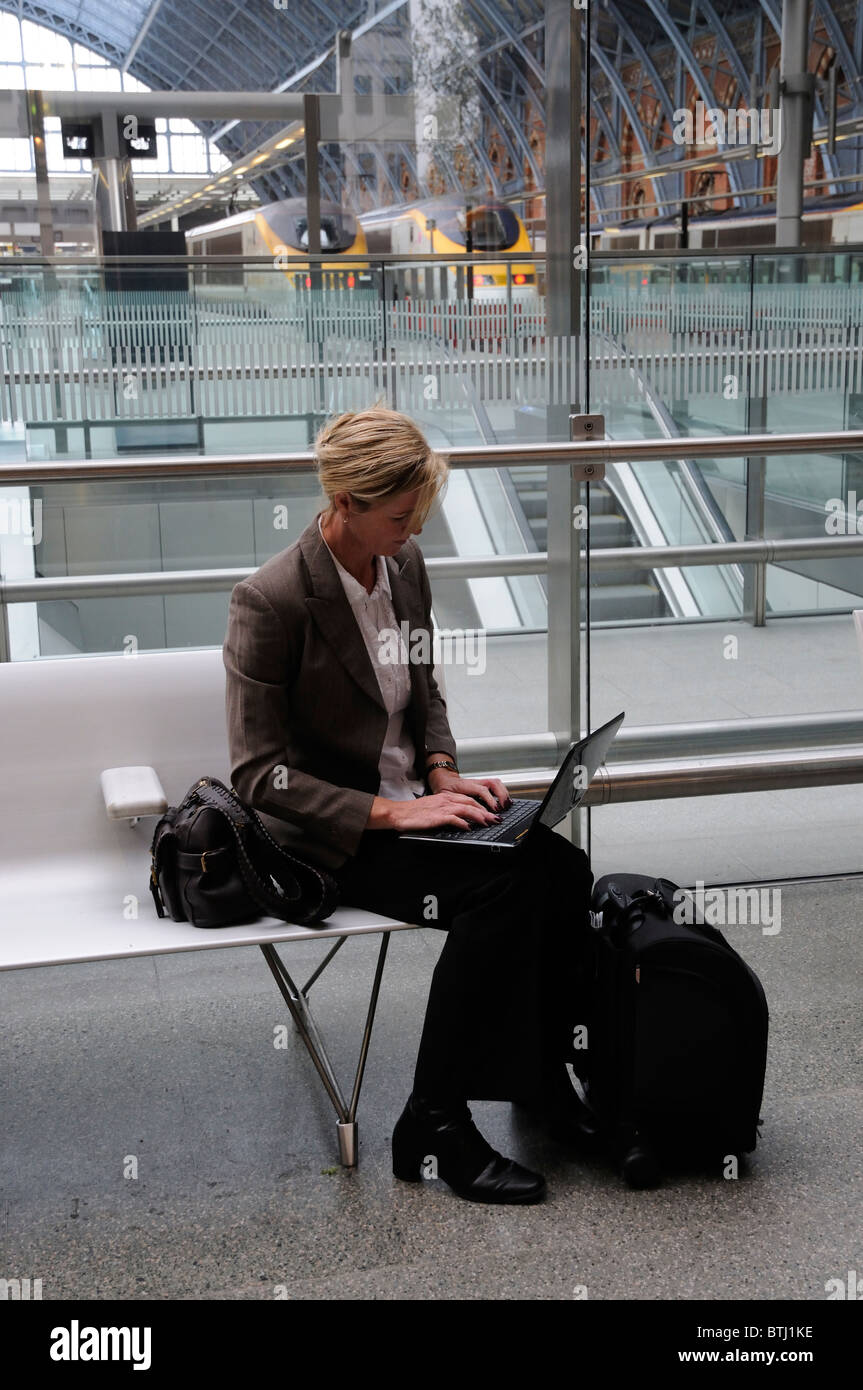 Portrait of a business woman sitting on a seat using a laptop computer ...