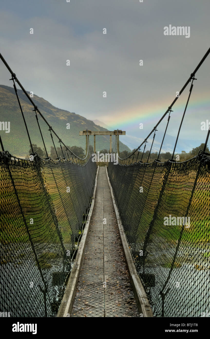 A footbridge leading towards a beautiful rainbow Stock Photo - Alamy