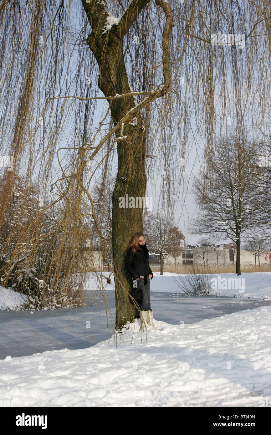 Young woman leaning against tree sad face Stock Photo - Alamy
