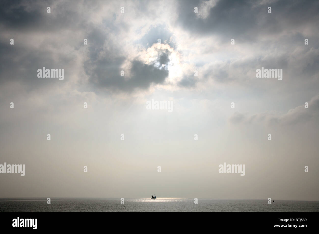 A boat far out at sea with light breaking through the clouds Stock ...