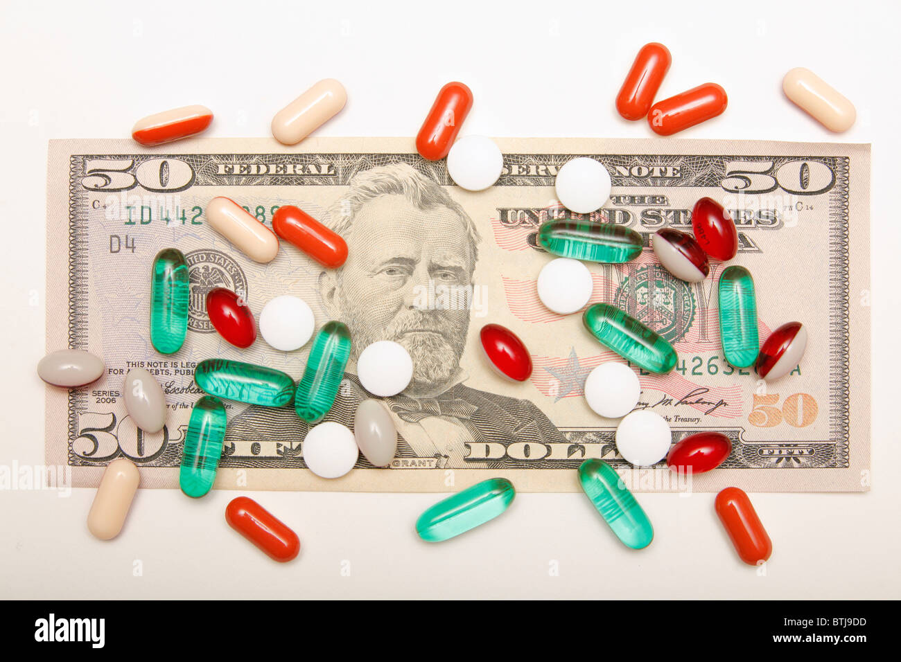 medication pills tablets and softgels on 50 US dollar bill on gray ...