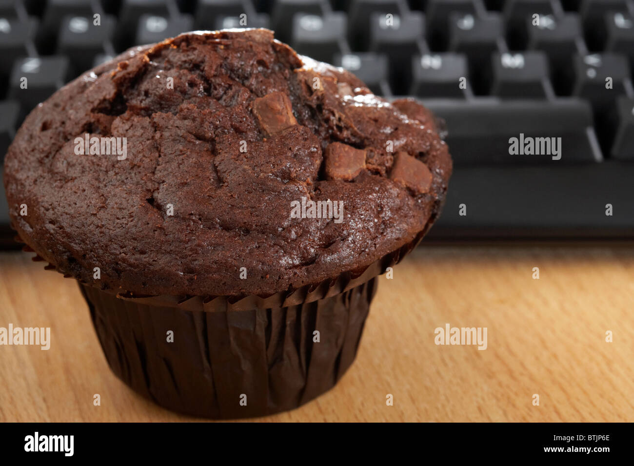 double choc chip chocolate muffin in front of computer keyboard at ...