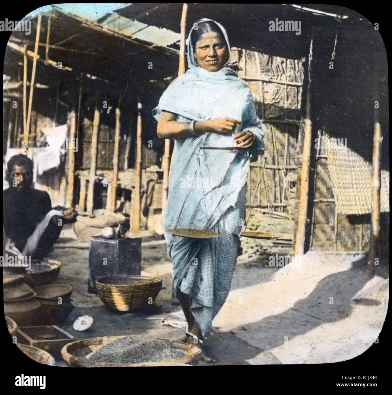 India, a young woman street vendor holding measuring scales, hand ...