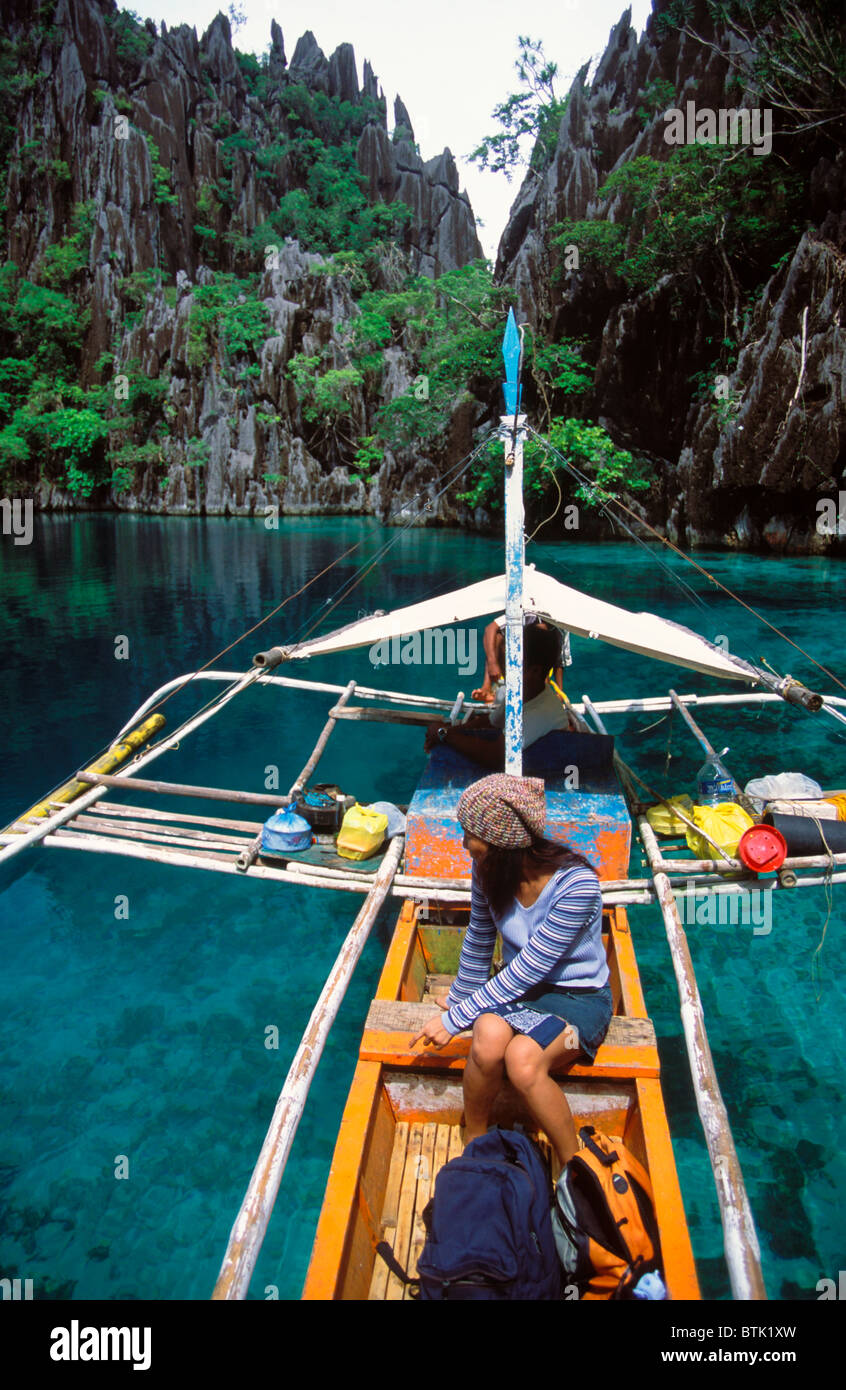 A tourist in an outrigger canoe boat in a beautiful lagoon in Coron ...