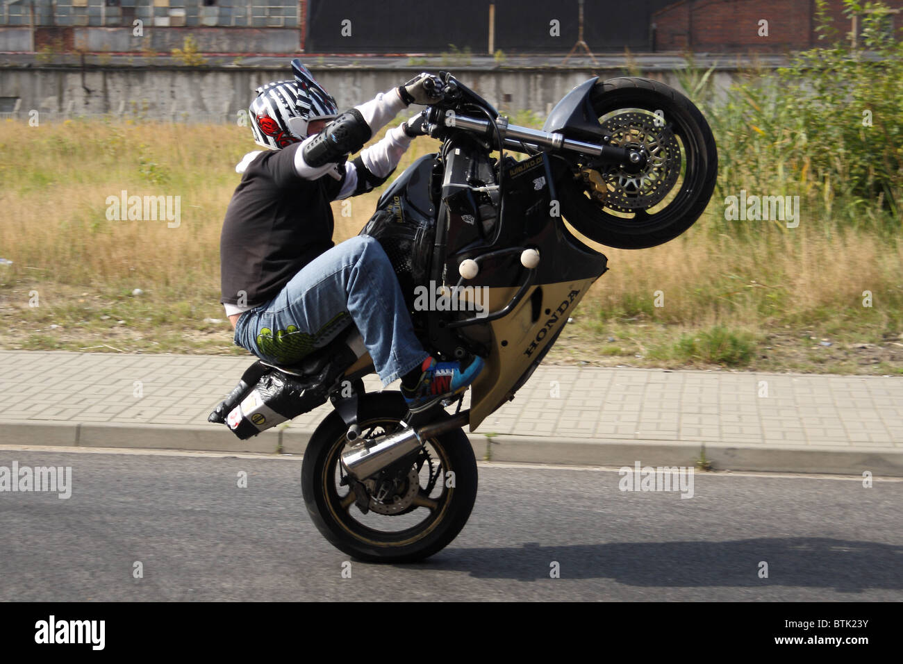 Stunt motorbiker balancing on his Honda motorbike on rear wheel Stock ...