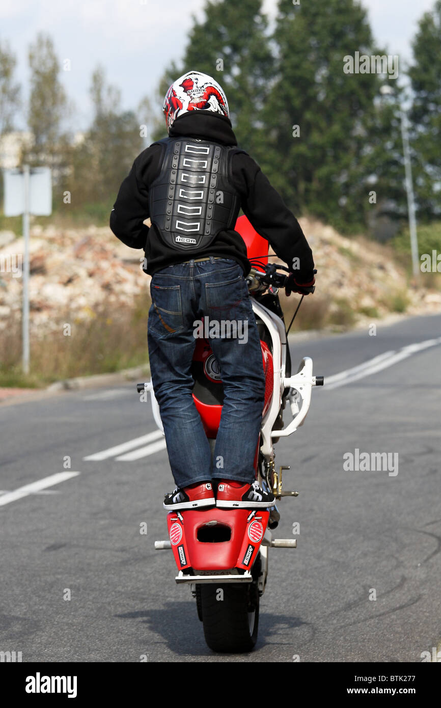 Stunt motorbiker balancing on his Honda motorbike on rear wheel Stock ...