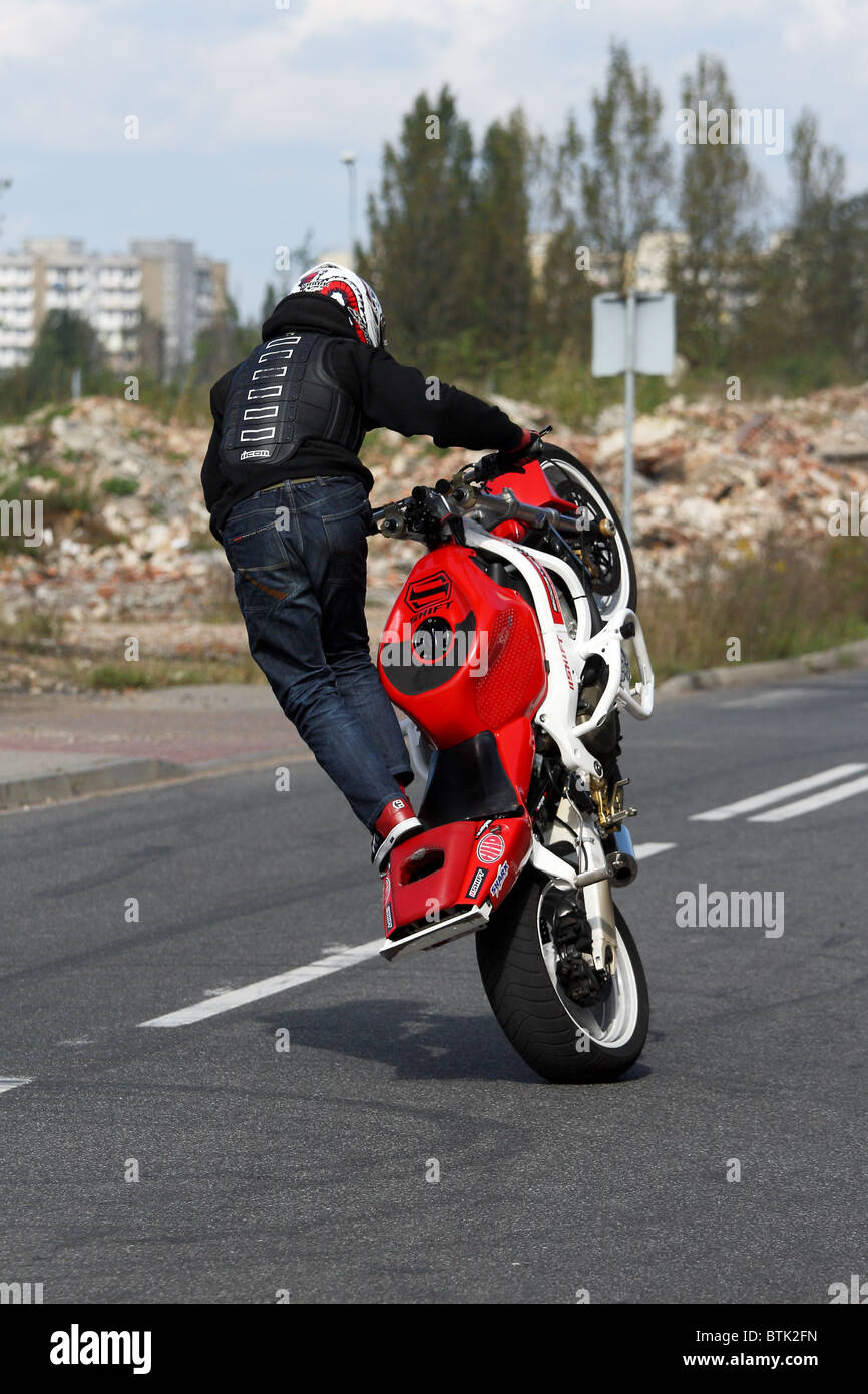 Stunt motorbiker balancing on his Honda motorbike on rear wheel Stock ...