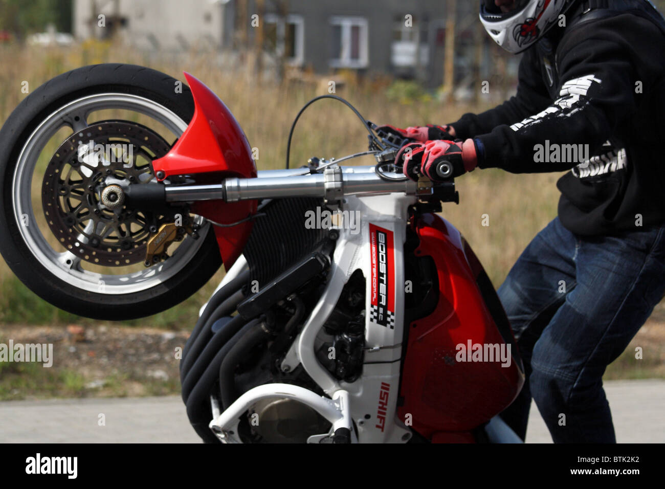 Stunt motorbiker balancing on his Honda motorbike on rear wheel Stock ...