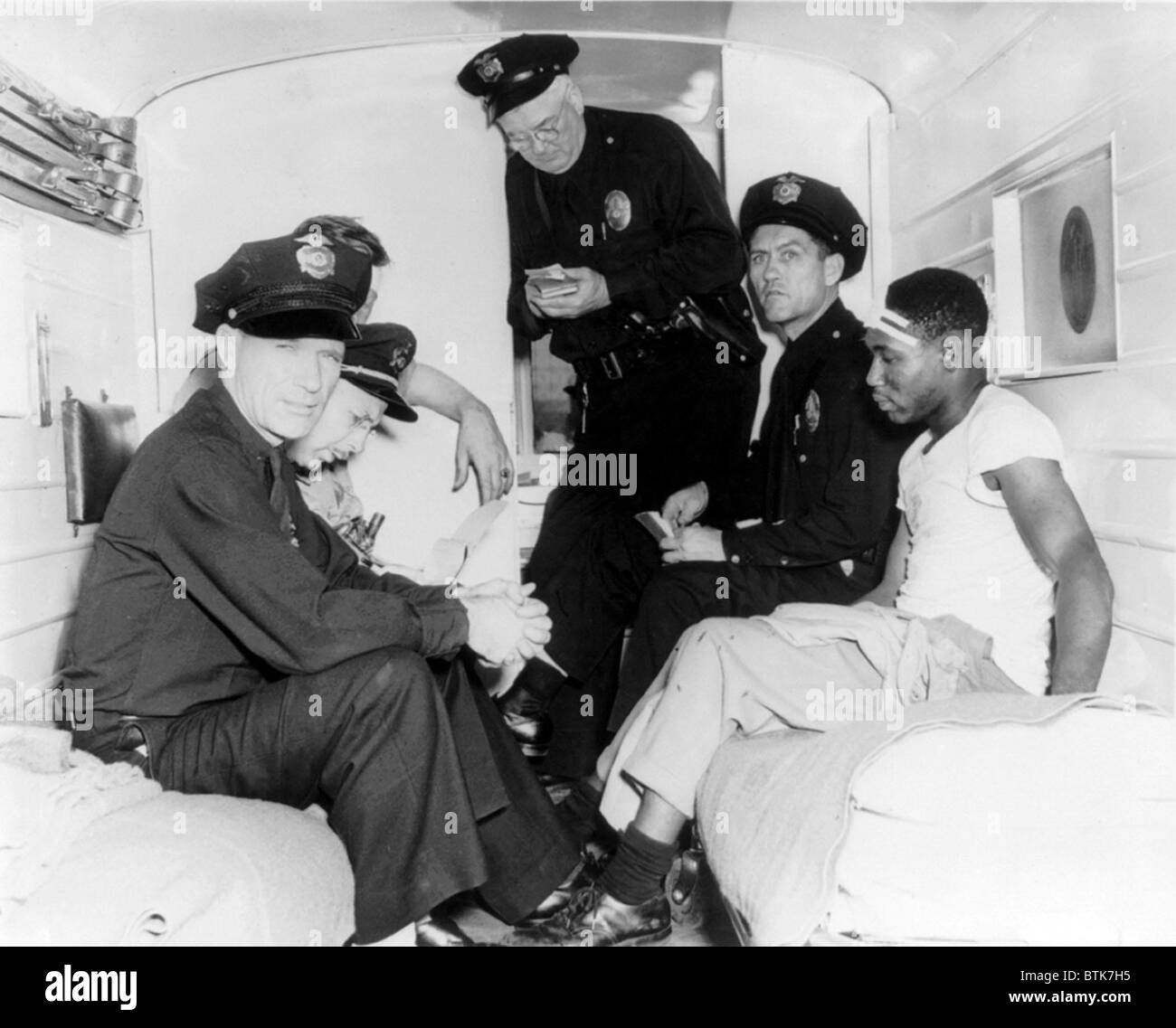 Policemen and wounded African American man inside police ambulance ...