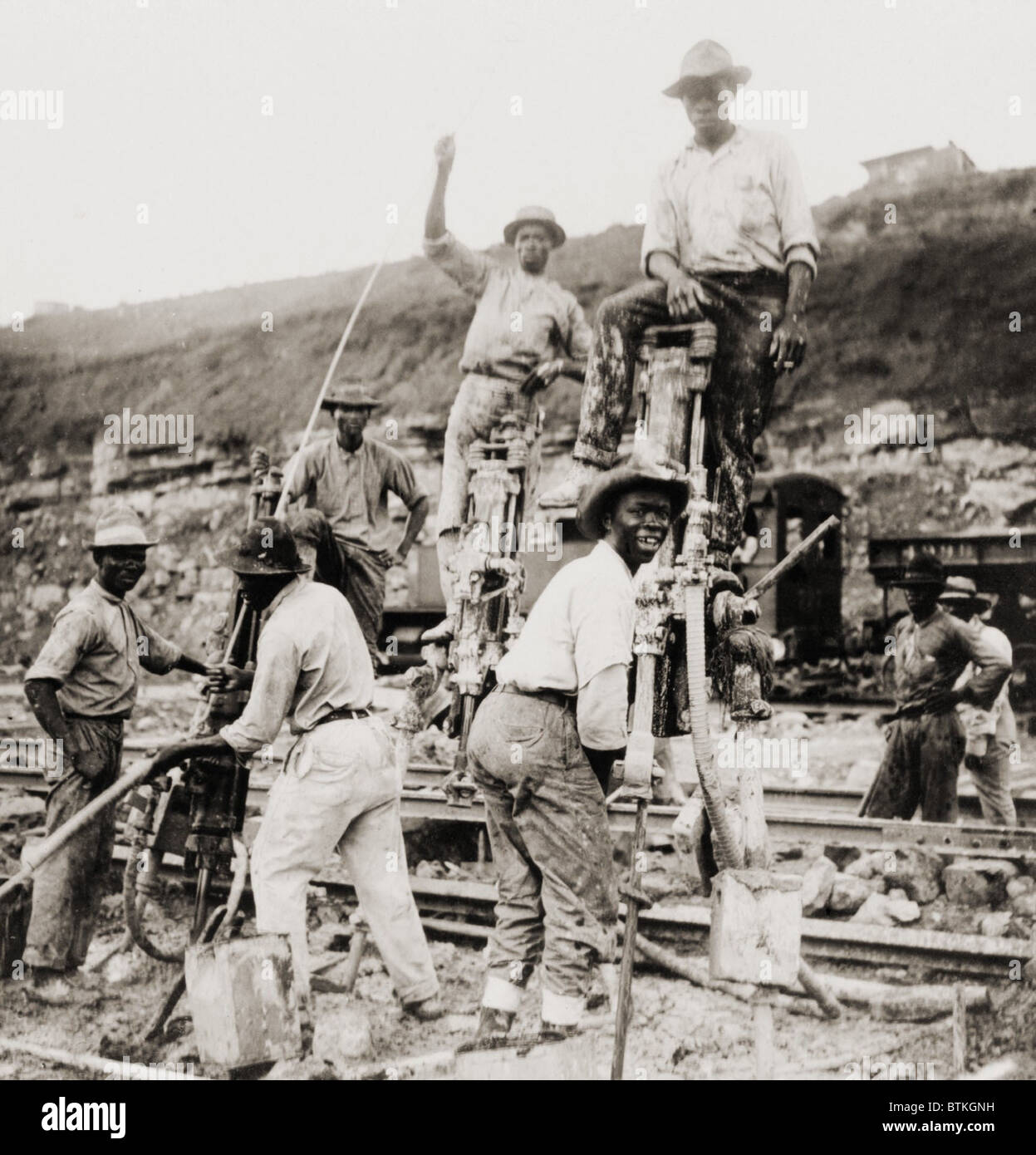 Afro-Panamanian construction workers boring through rock with tripod ...