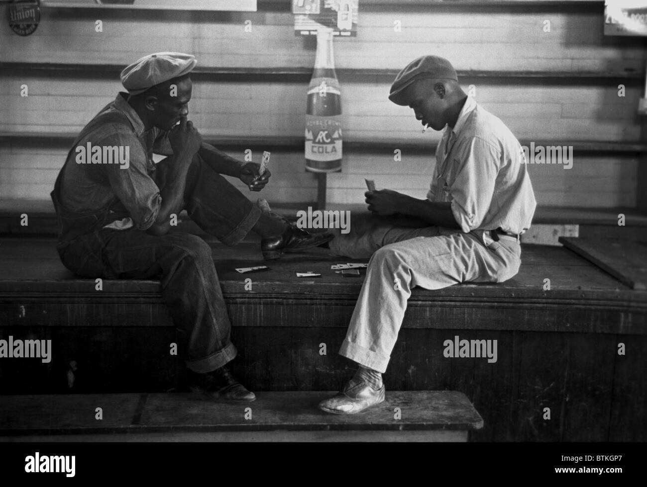 African American young men play a card game of Coon Can, in a store ...
