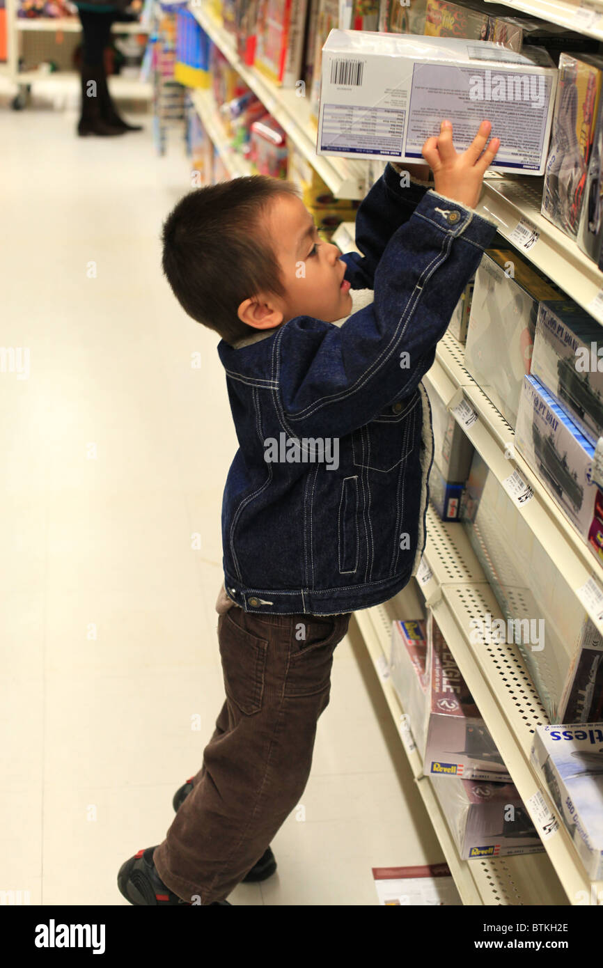 A boy reaching for a toy in toy store Stock Photo - Alamy