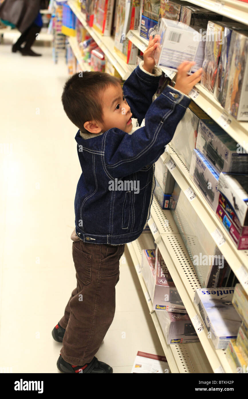 A boy reaching for a toy in toy store Stock Photo - Alamy