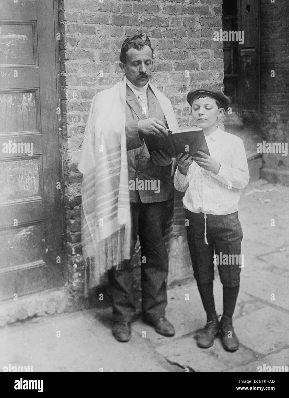 Jewish man wearing a prayer shawl and boy reading from Hebrew Bible on ...
