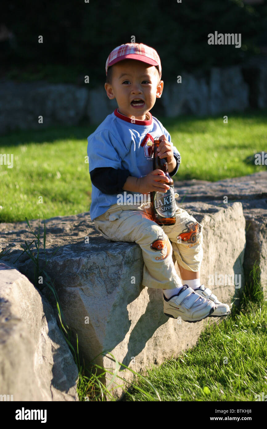 A toddler boy holding a beer bottle Stock Photo - Alamy
