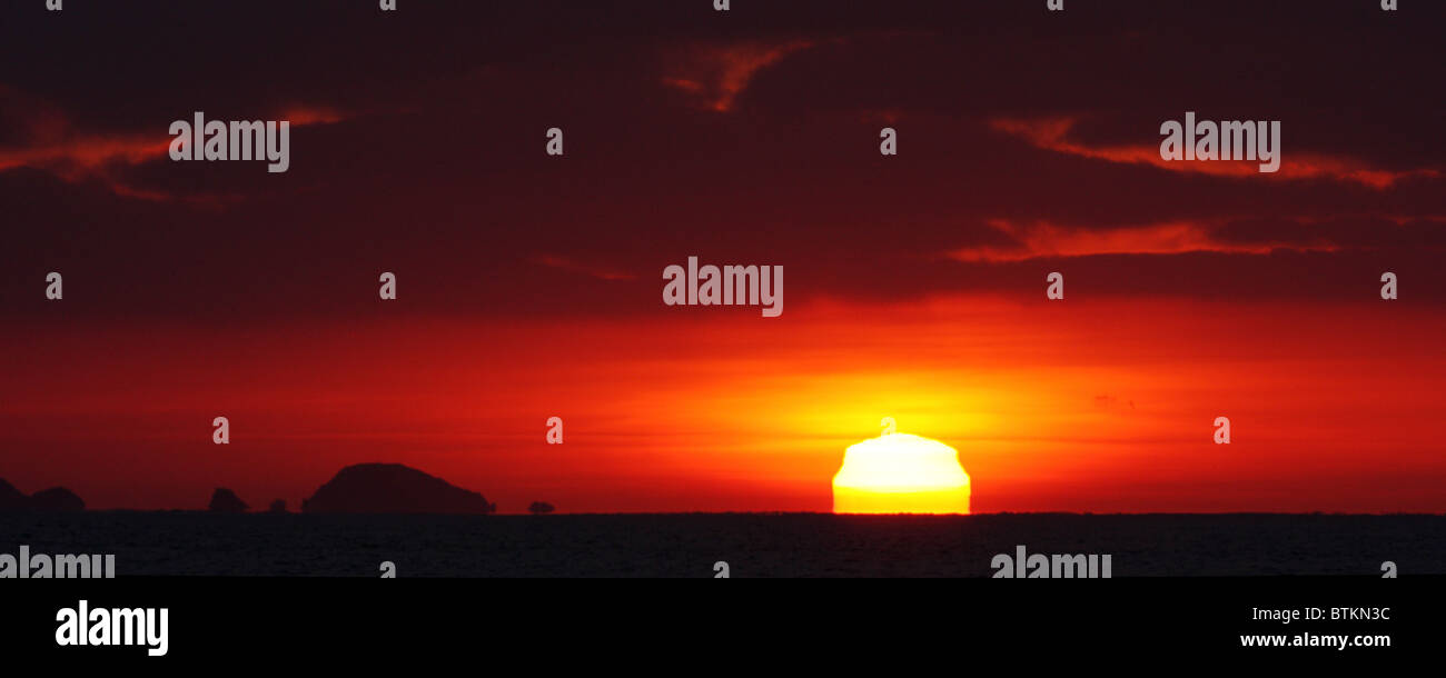 The sun creates a mirage as it rises over Sark Stock Photo - Alamy