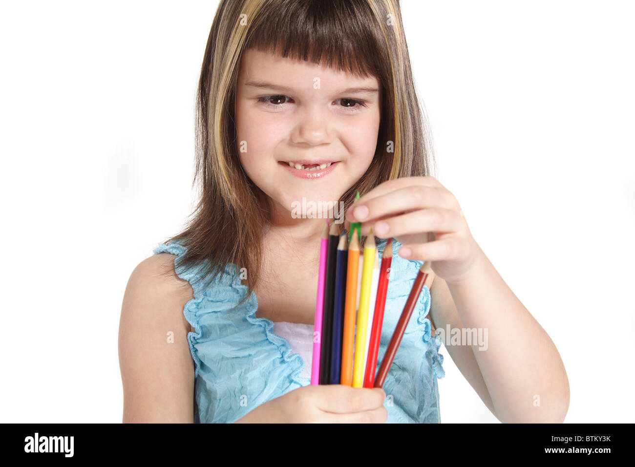 A young girl choosing a colorful crayon. All isolated on white ...